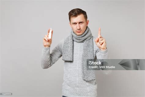 회색 스웨터에 엄격한 젊은 남자 스카프 코 잡고 포인팅 검지 손가락에 고립 된 회색 배경을 삭제 합니다 건강 한 생활 습관 병