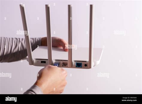 The Back View Of Router Showing The Lan Internet Port And The Hand Is Pluging In The Land Cable