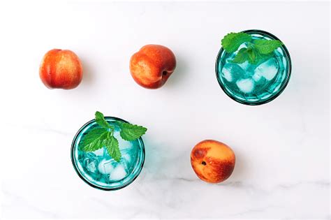 차가운 음료와 얼음 조각이있는 아름다운 빈티지 청록색 안경 2 개와 신선한 녹색 민트 잎과 흰색 대리석 테이블에 3 개의