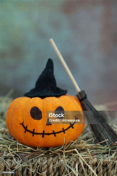 모델 빗자루 옆에 펠트 마녀 모자를 입은 호박 머리의 이미지 건초 더미에 무서운 할로윈 얼굴 잭 O랜턴 0명에 대한 스톡 사진 및 기타 이미지 Istock