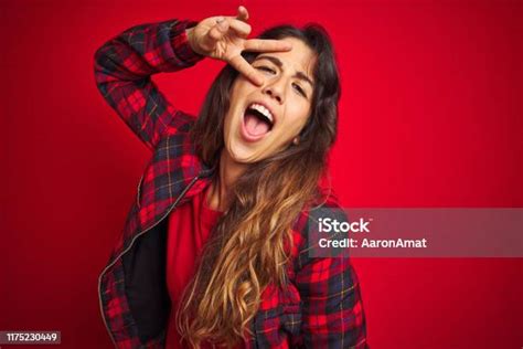 빨간 고립 된 배경 위에 서있는 캐주얼 재킷을 입은 젊은 아름다운 여성은 손 짓으로 상징적 인 총을 들고 살인 사격 무기 화가 난 얼굴을 연주합니다 가리키기에 대한 스톡