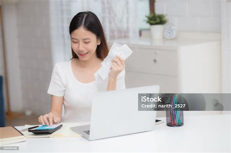 젊은 아시아 여성은 가정에서 책상에 계산기로 금융 가정을 계산 여자 확인 청구서 및 비용 가계 부채 폐쇄 세금 및 회계 비즈니스 개념에 대한 성공을 확인합니다 계산기에 대한