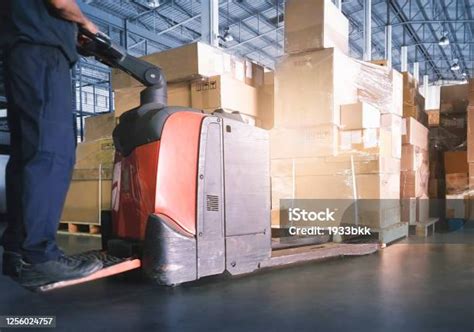 전기 지게차 팔레트 잭 을 운전하는 창고 노동자는 선적 상자를 언로딩합니다 화물 수출 및 배송 창고 물류 및 운송 공장 산업 건물에 대한 스톡 사진 및 기타 이미지 Istock