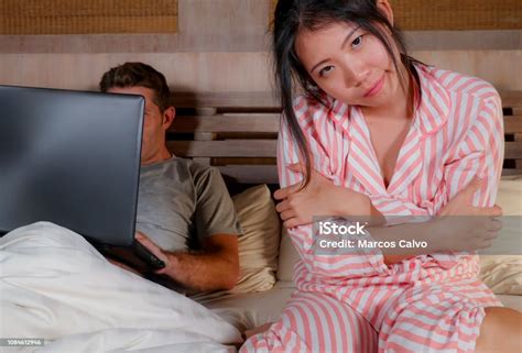 워커 홀 릭 남편에 의해 침대에 분노 하 고 좌절 한국 여자 무시 또는 인터넷 소셜 미디어 중독자 아시아 몇 문제 충돌에서 여자를 무시 하 고 침대에서 노트북으로 네트워킹