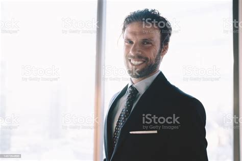 성공적인 경력에 만족하는 트렌디 한 복장으로 회사에 웃고있는 백인 남자 주인의 절반 길이 초상화 창문 근처 사무실에서 카메라를 보며 웃고있는 쾌활한 남성 기업가 30 대
