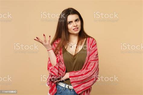 캐주얼 한 옷 카메라를 찾고에 자극 젊은 여자의 초상화 스튜디오에서 파스텔 베이 지 벽 배경에 고립 된 손을 확산 사람들은 진심으로 감정 라이프 스타일 개념입니다 복사