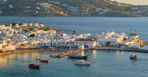 유명한 풍차가 있는 그리스 관광 휴양지의 미코노스 타운 전망 보트와 요트 일몰이 있는 항구 미코노스 키클라데스 제도 그리스 수평 카메라 패닝 사용 사진