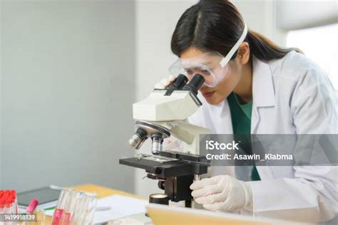 여성 의학 의사 또는 연구 과학자 실험실과학 실험에서 현미경을 통해 찾고 생물학 화학 샘플을 연구하기위한 화학 액체를 포함하는 실험실 유리 제품 20 24세에 대한 스톡