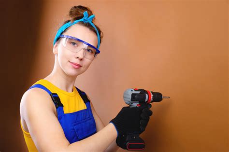 갈색 배경에 그녀의 손에 드라이버와 바지 바지와 고글매력적인 젊은 여자 리노베이션 및 건설 개념 카메라를 바라보는 스튜디오 초상화 건설 산업에 대한 스톡 사진 및 기타