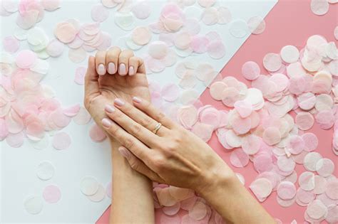 세련 된 트렌디 한 여성 핑크 매니큐어입니다 아름다운 젊은 여성은 색종이와 텍스트 장소와 분홍색과 흰색 배경에 손을 최소한의 창조적 인 개념 플랫 레이 상단 보기 모형 복사