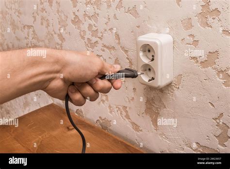 A Man Hand Inserts Or Removes A Plug From An Outlet In A Modern Interior Safe Use Of Electrical