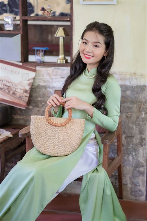 가구 가방 검은 머리 고요한 긴 머리 녹색 드레스 매력 문화 패션 문화적 복장 미소 짓는 부드러운 조명 성인 여성 세련된 디자인 세련된 복장 수직