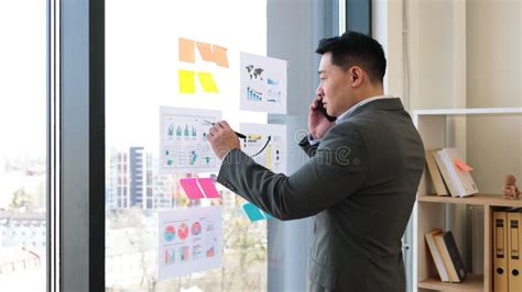 Asian Businessman Analyzing Charts While On Phone Call Stock Footage