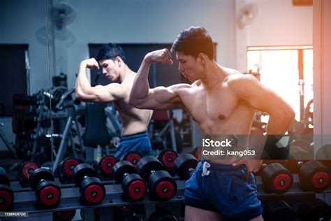 아시아 잘생긴 젊은 근육 질 아시아 사람 운동 보디 빌딩 앞에서 유리 체육관에서 남자는 그의이 두 근 근육을 훈련 체육관에서 카메라에 시체를 보여주는 체육관 개념에서 운동