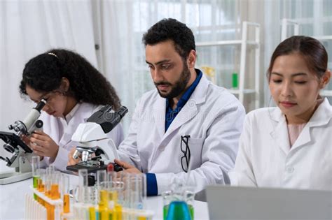 Scientist Team In White Laboratory Coat Working With Microscope And Laptop For Research In