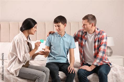 Parents Talking With Their Teenage Son About Contraception In Bedroom Sex Education Concept