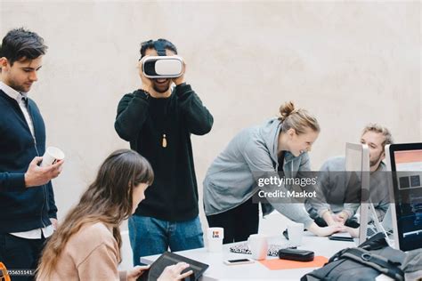Male Computer Programmer Using Vr Glasses While Colleagues Working In