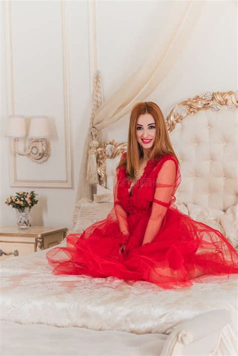 Sensual Red Hair Woman In A Red Lace Boudoir Dress On A Bed Stock Image