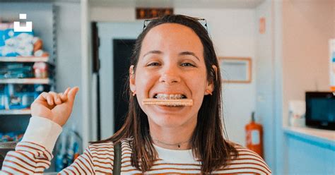 그녀의 입에 크래커와 함께 갈색과 흰색 줄무늬 스웨터를 입은 여자 사진 Unsplash의 무료 사람의 이미지