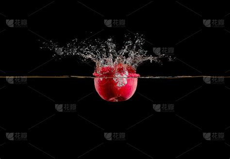 红苹果在黑色背景下落入水中