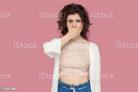 충격의 초상화 아름 다운 갈색 머리 젊은 여 자가 캐주얼 스타일에서 곱슬 헤어스타일로 그녀의 입을 덮고 카메라를 보고 20 29세에 대한 스톡 사진 및 기타 이미지 Istock
