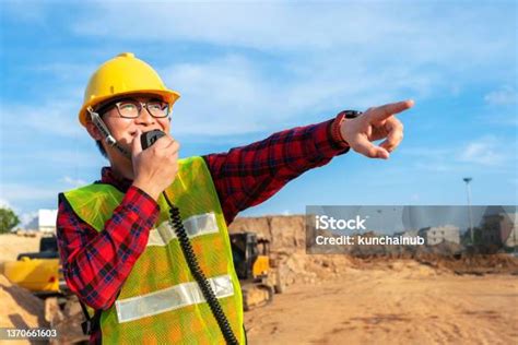 아시아 기술자 토목 엔지니어가 무전기로 팀과 이야기하고 엔지니어링 현장 배경에 굴삭기와 운송 건설 공사 프로젝트에 대한 검사 지점에서 포인트 개발에 대한 스톡 사진 및 기타