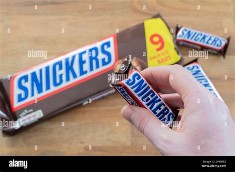 Hand Holding A Snickers Bar With A Snickers Packet In The Background Snickers Is Owned By Mars