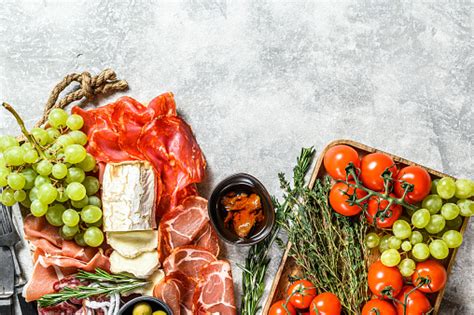 이탈리아 안티 파스토 Prosciutto 햄 파르마 염소와 카망베르 치즈 올리브 포도와 나무 도마 Antipasti 회색 배경입니다 맨 위 보기 복사 공간 0명에 대한 스톡