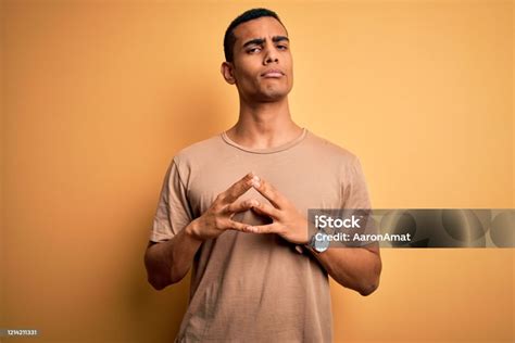 노란색 배경 에 서 캐주얼 티셔츠를 입고 젊은 잘 생긴 아프리카 계 미국인 남자 함께 손을 함께 손가락 은 편안 하 고 쾌활 한 미소 교차 성공과 낙관적 T 셔츠에 대한