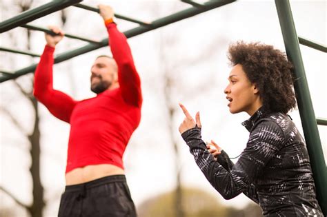 그 옆에 서 있는 그의 여성 코치와 함께 도시 공원에서 원숭이 바에서 풀업을 하 고 시간을 측정 하는 남성 선수 버프 2명에 대한 스톡 사진 및 기타 이미지 Istock