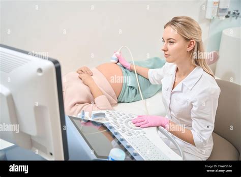 Young Qualified Sonographer Making Ultrasound To Pregnant Woman Stock