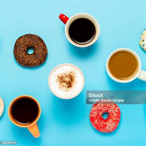뜨거운 음료 커피 카푸치노 파란색 배경에 차를 곁들인 맛있는 도넛과 컵 과자 빵집 패스트리 커피숍 회의 친구 친절한 팀의 개념 사각형 플랫 레이 상단 보기 도넛에 대한 스톡