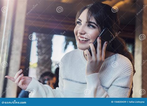 Young Woman Talking On Cell Phone While Sitting Alone In Coffee Shop