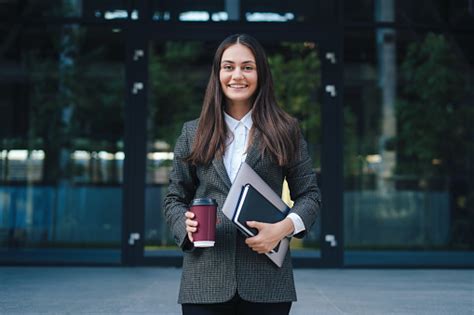 노트북 컴퓨터를 들고 회사 건물 밖에 서있는 뜨거운 음료를 가져 오는 아름다운 백인 사업가 라이프 스타일 및 작업 개념 카메라 보기 25 29세에 대한 스톡 사진 및 기타