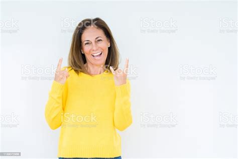 고립 된 배경 위에 노란 스웨터를 입고 아름 다운 중세 여 자가 손으로 바위 기호를 하 고 미친 표정으로 외치는 음악 스타