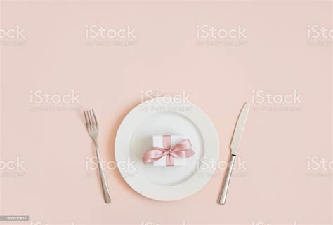 분홍색 배경에 접시에 선물과 축제 테이블 설정입니다 로맨틱 또는 결혼식 저녁 식사 발렌타인 데이 또는 어머니의 날 배경입니다