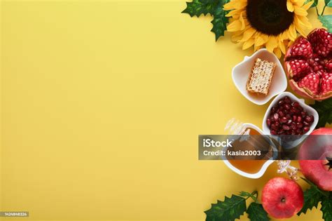 로쉬 하샤나 익은 석류 사과 꿀 해바라기 노란색 배경에 노란색 꽃 상징을 가진 작곡 유태인 Rosh Hashanah 휴일 속성 복사 공간이 있는 위쪽 보기입니다 0명에 대한