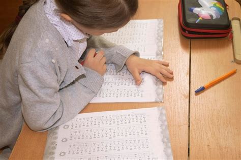 Premium Photo A Girl Solves Tasks In A Math Notebook In A Classroom