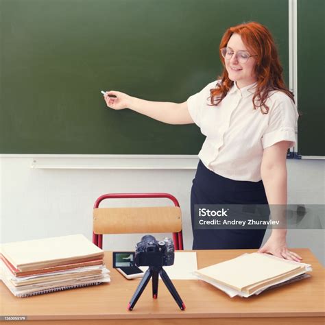 행복한 선생님이 교실에 서서 칠판에 분필로 보여줍니다 학교에서 온라인 수업 및 카메라에 수업의 비디오 녹화 복사 공간 교사 교육 관련 직업에 대한 스톡 사진 및 기타 이미지