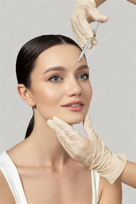 Premium Photo A Beautiful Girl Makes An Injection Of Botox On A Gray Background