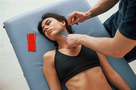 테이블 위에 누워 피부에 키네시오 테이프를 붙이는 생리학자를 방문하는 여성 25 29세에 대한 스톡 사진 및 기타 이미지 25 29세 2명 30 34세 Istock