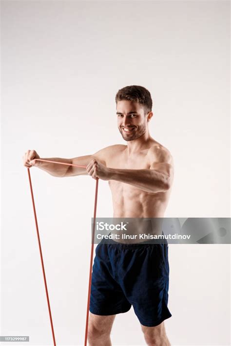 그의 손에 체조 탄성 밴드와 흰색 배경에 수염을 가진 젊은 스포티 한 남자 고무 밴드로 훈련 강사에 대한 스톡 사진 및 기타