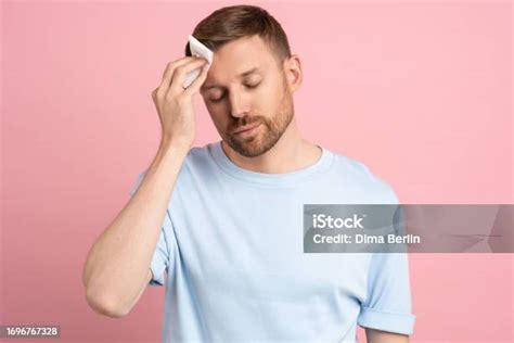 과열 피곤한 남자는 젖은 물티슈를 머리에 대고 땀을 흘리며 스튜디오의 분홍색 벽에 건강에 해로운 느낌을 줍니다 40 44세에 대한 스톡 사진 및 기타 이미지 Istock