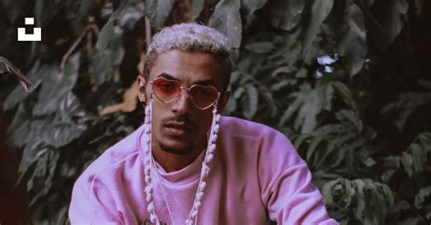 분홍색 스웨터와 디스트레스드 블루 데님 청바지를 입은 남자가 나무 근처의 회색 콘크리트 블록에 앉아 근접 촬영 사진