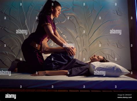 Focused Massage Therapist Stretching Lower Extremities Of Female