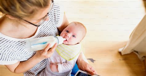 알아볼 수 없는 어머니가 아기 아들을 팔에 안고 태블릿 병에 우유를 넣고 있는 클로즈업 사진 Unsplash의 아름다움 이미지