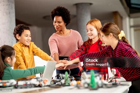 로봇 교실에서 노트북 프로그래밍 전기 장난감과 로봇과 함께 아프리카 계 미국인 여성 과학 교사와 행복한 아이들 10 11세에