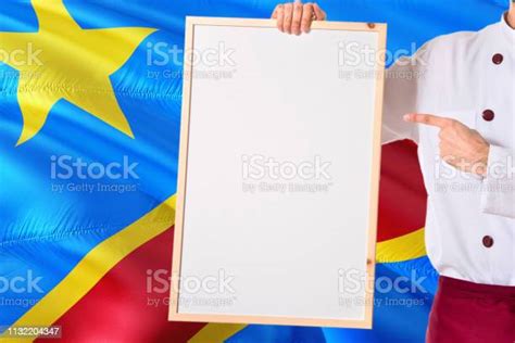 콩고 플래그 배경에 빈 화이트 보드 메뉴를 들고 Congolese 요리사 텍스트에 대 한 균일 한 포인팅 공간을 착용 요리 고급 요리에 대한 스톡 사진 및 기타 이미지
