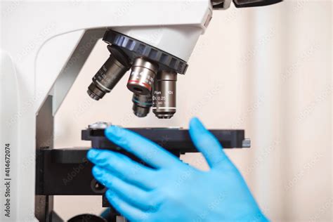 Laboratory Assistant In Blue Gloves Examines A Semen Sample Under A Microscope Shallow Depth Of