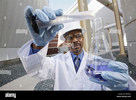 Scientist Pouring Liquid Into A Flask From A Graduated Cylinder Stock
